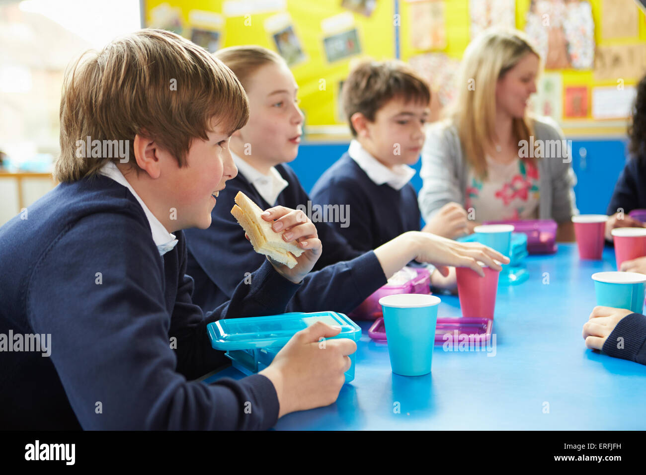 Schoolchildren With Teacher Sitting At Table Eating Lunch Stock Photo ...