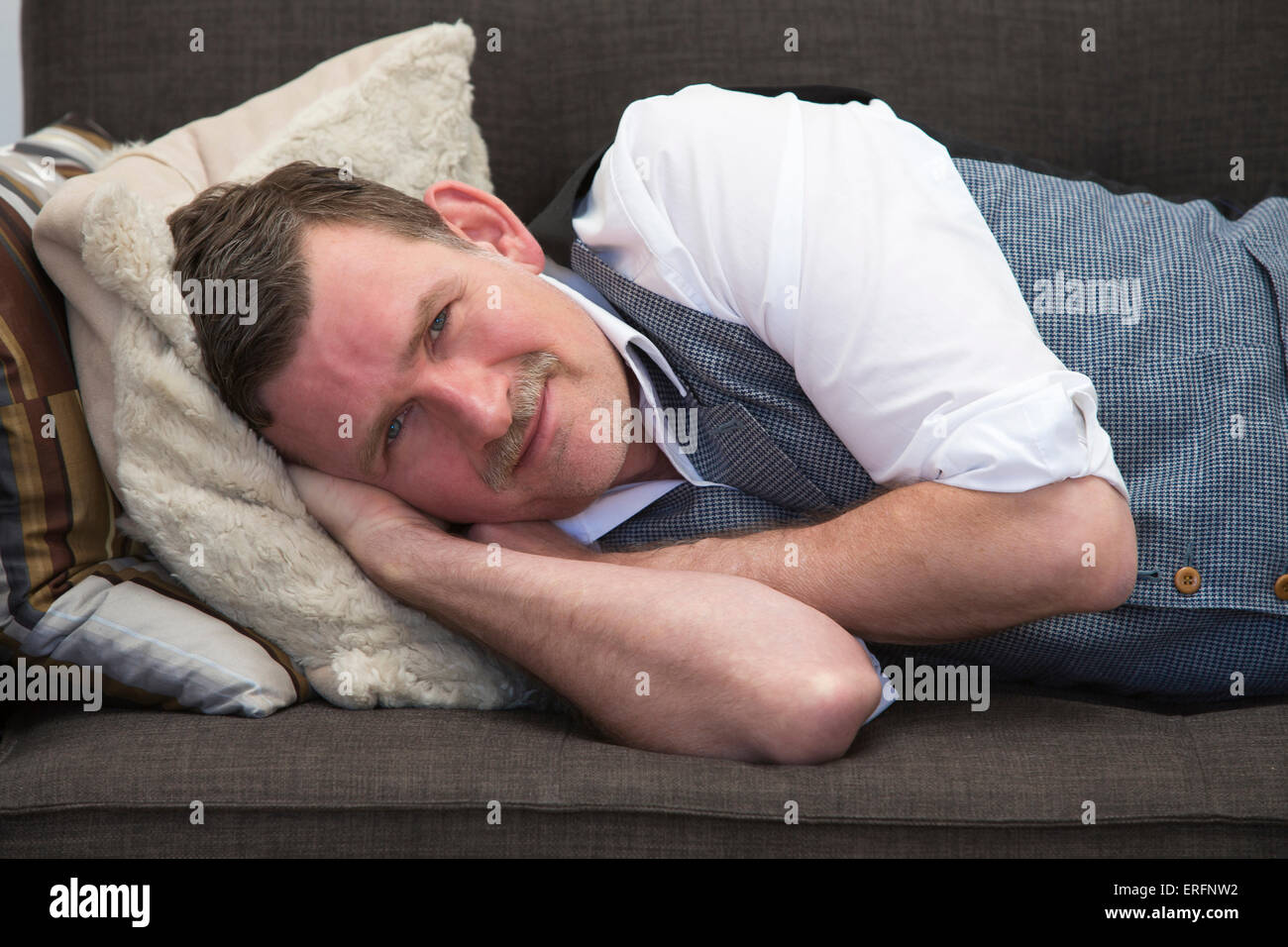 Smiling man resting on couch hi-res stock photography and images - Alamy