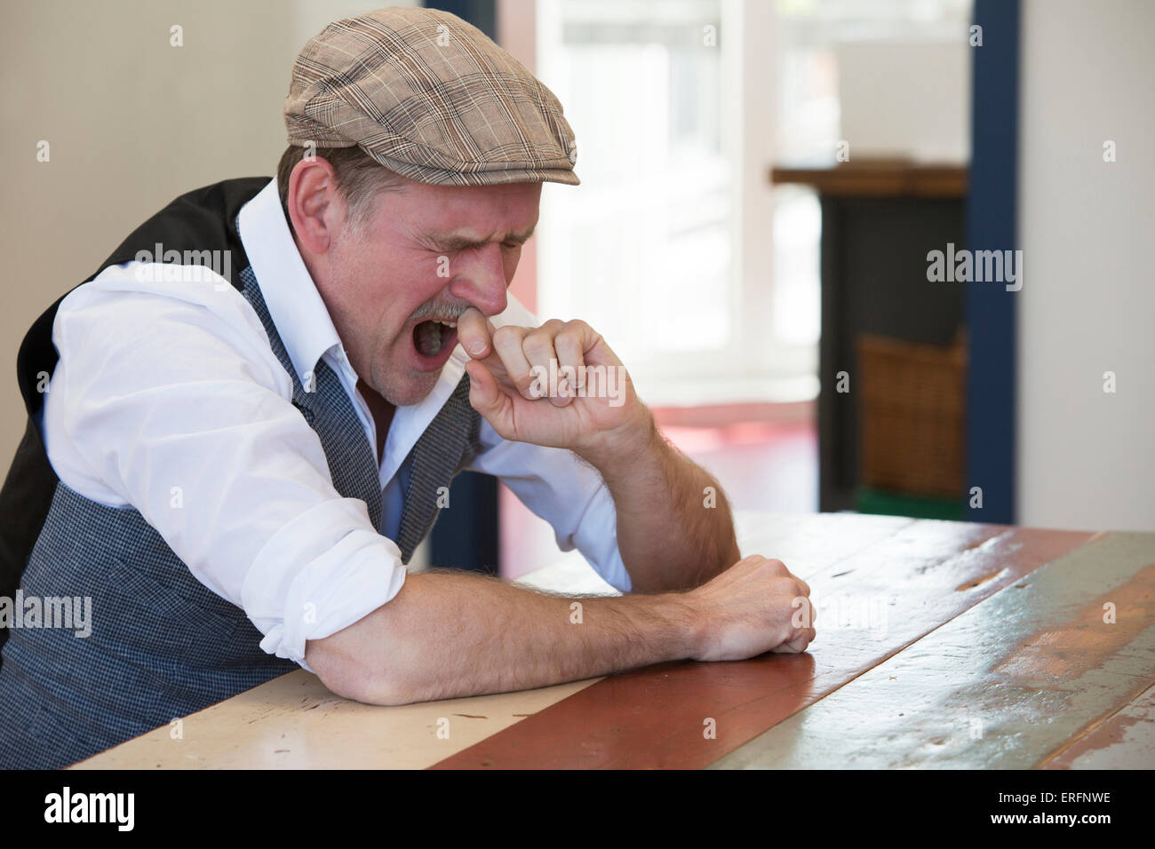 man in his 50's sitting at table and is yawning Stock Photo - Alamy