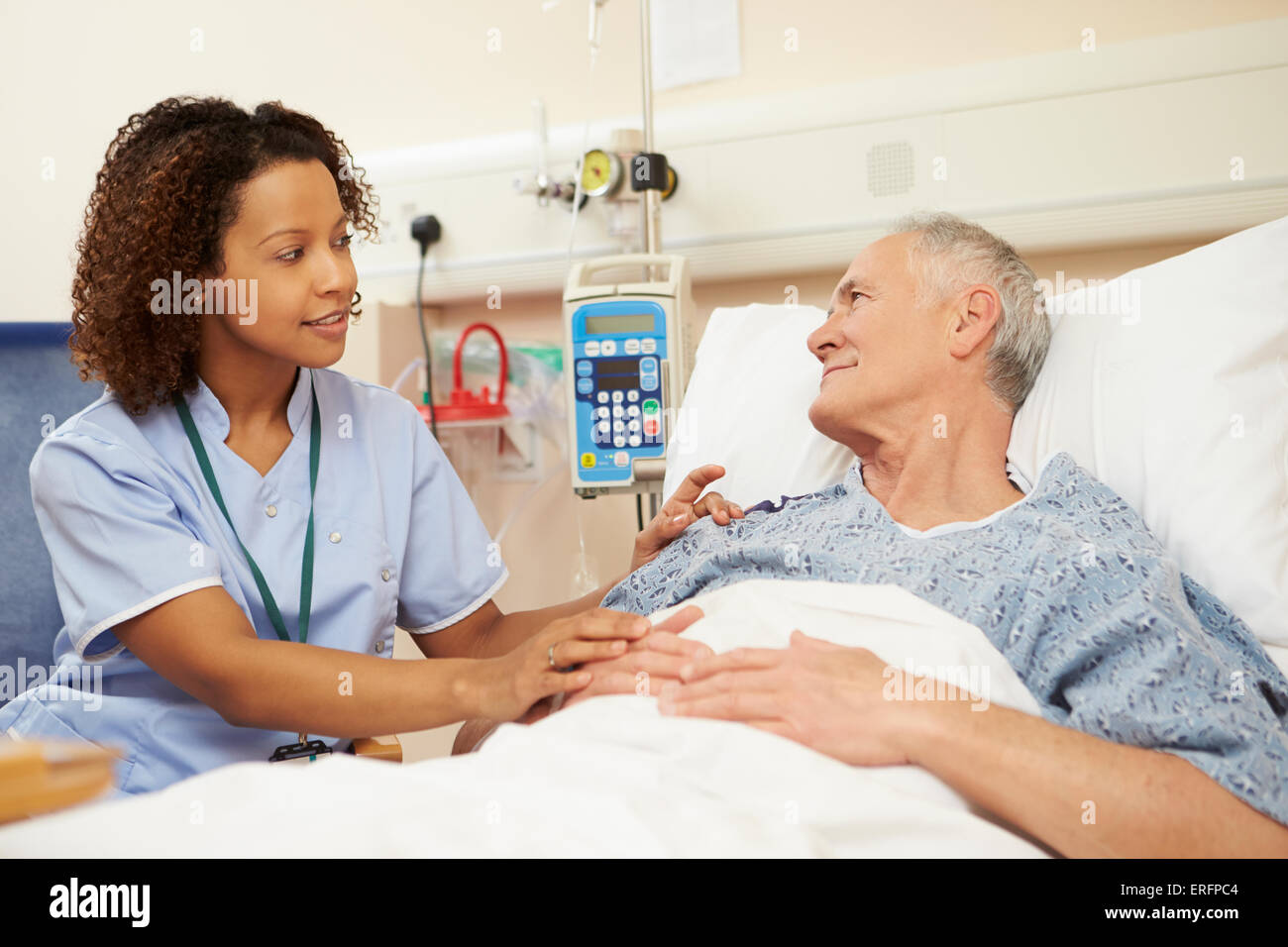 Nurse Sitting By Male Patient's Bed In Hospital Stock Photo - Alamy