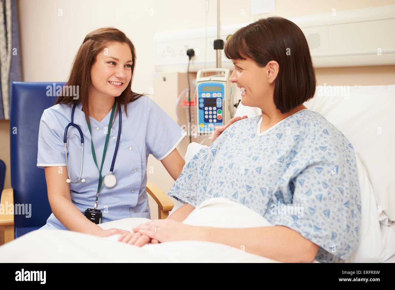 Nurse Sitting By Female Patient's Bed In Hospital Stock Photo - Alamy