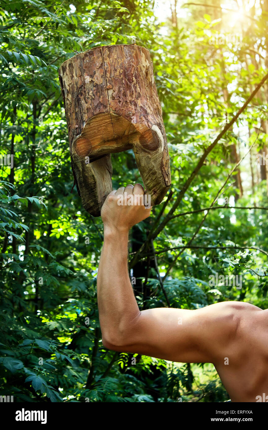 Muscular man workout with wooden kettlebell in forest. Eco-friendly ...