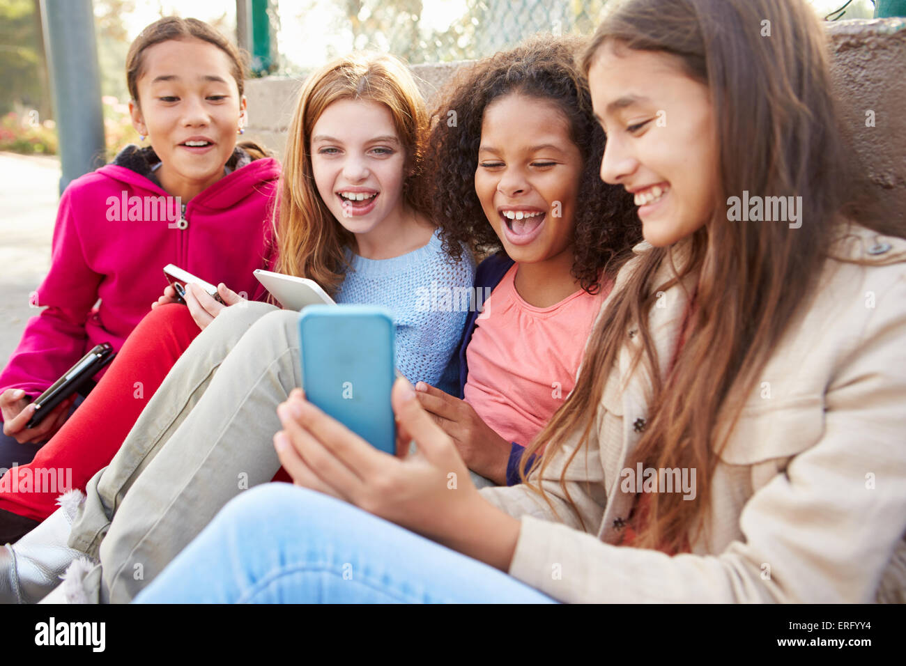 Young Girls Using Digital Tablets And Mobile Phones In Park Stock Photo ...