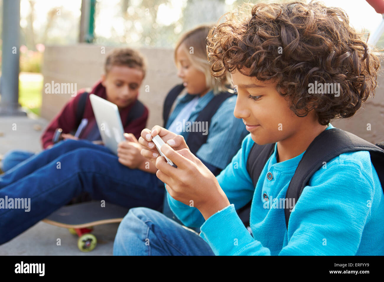 Young Boys Using Digital Tablets And Mobile Phones In Park Stock Photo ...
