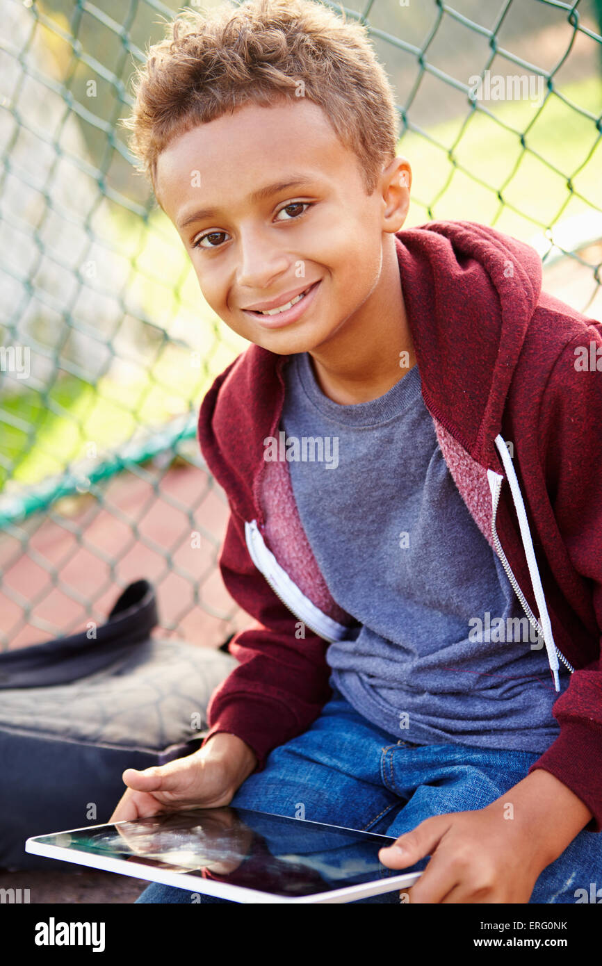 Young Boy Using Digital Tablet Sitting In Park Stock Photo - Alamy