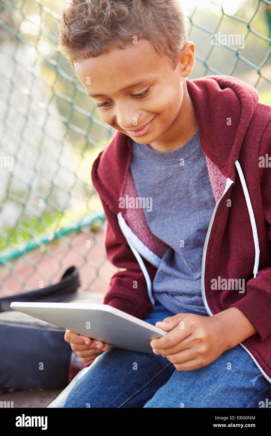 Young Boy Using Digital Tablet Sitting In Park Stock Photo - Alamy
