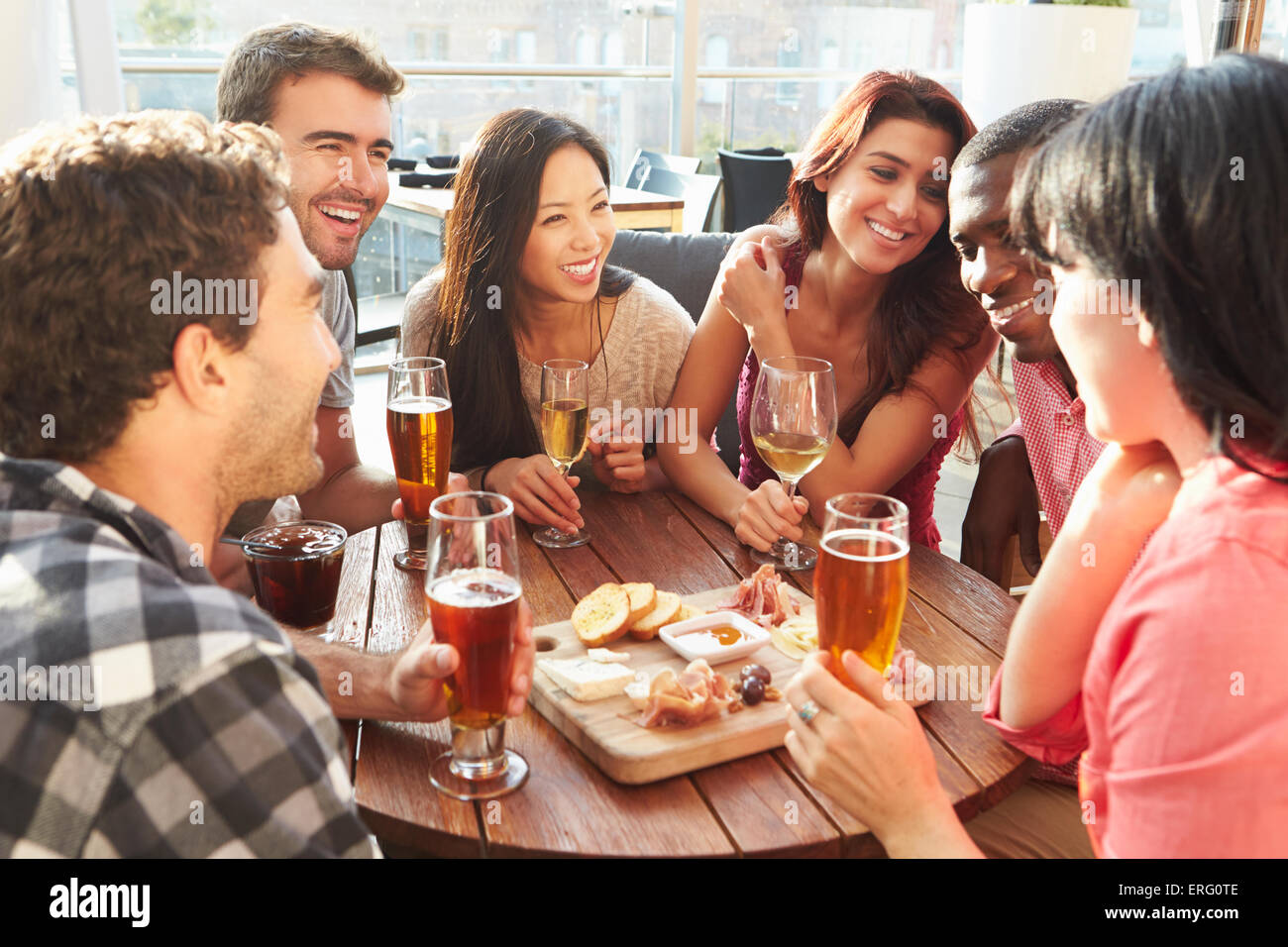 Group Of Friends Enjoying Drink And Snack In Rooftop Bar Stock Photo ...