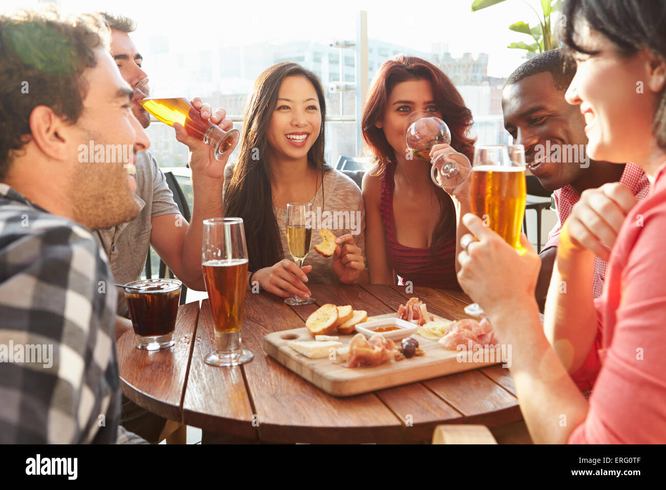 Group Of Friends Enjoying Drink And Snack In Rooftop Bar Stock Photo ...