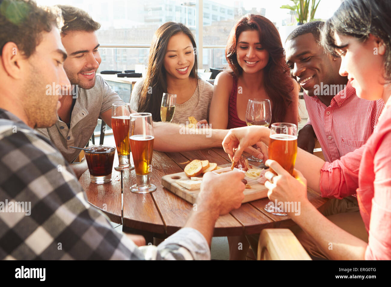 Group Of Friends Enjoying Drink And Snack In Rooftop Bar Stock Photo ...