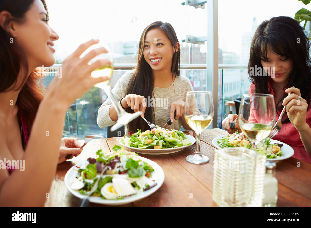 Three Female Friends Enjoying Lunch At Rooftop Restaurant Stock Photo ...