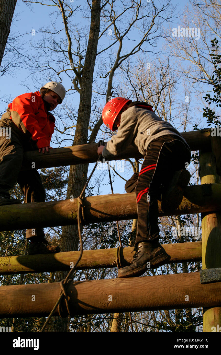 Child climbing over an obstacle with help from an instructor at a ...