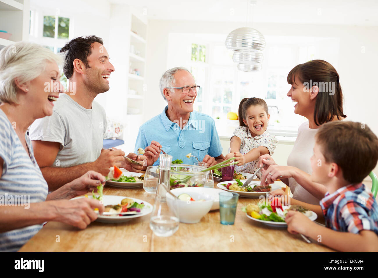 Multi Generation Family Eating Meal Around Kitchen Table Stock Photo ...