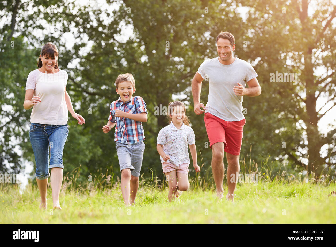 Smiling Family Running Across Summer Field Together Stock Photo - Alamy