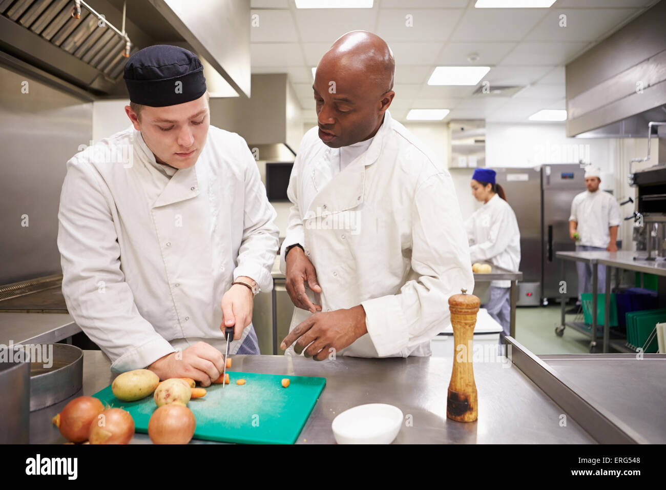Teacher Helping Students Training To Work In Catering Stock Photo - Alamy