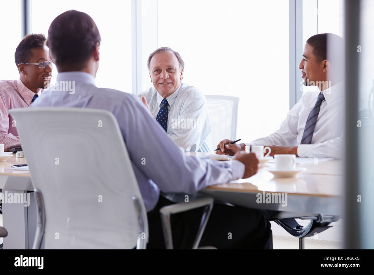 Four Businessmen Having Meeting Around Boardroom Table Stock Photo - Alamy