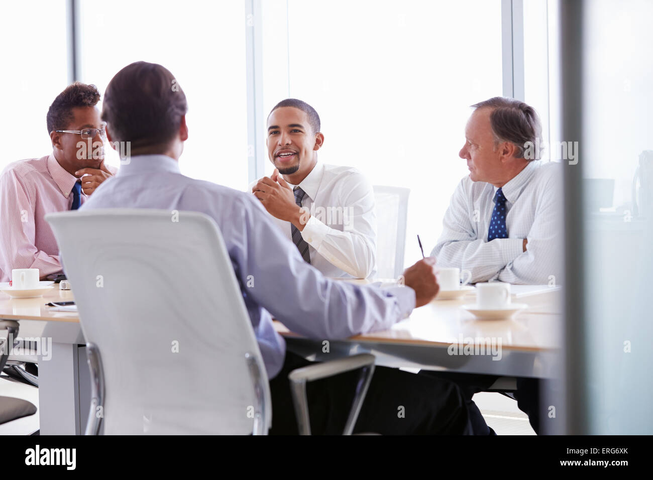 Four Businessmen Having Meeting Around Boardroom Table Stock Photo - Alamy