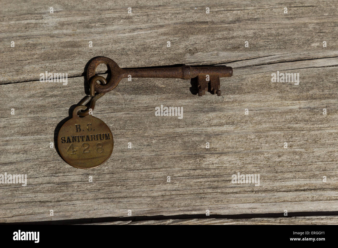 Old rusty skeleton key to a sanitarium / mental hospital on a wood ...
