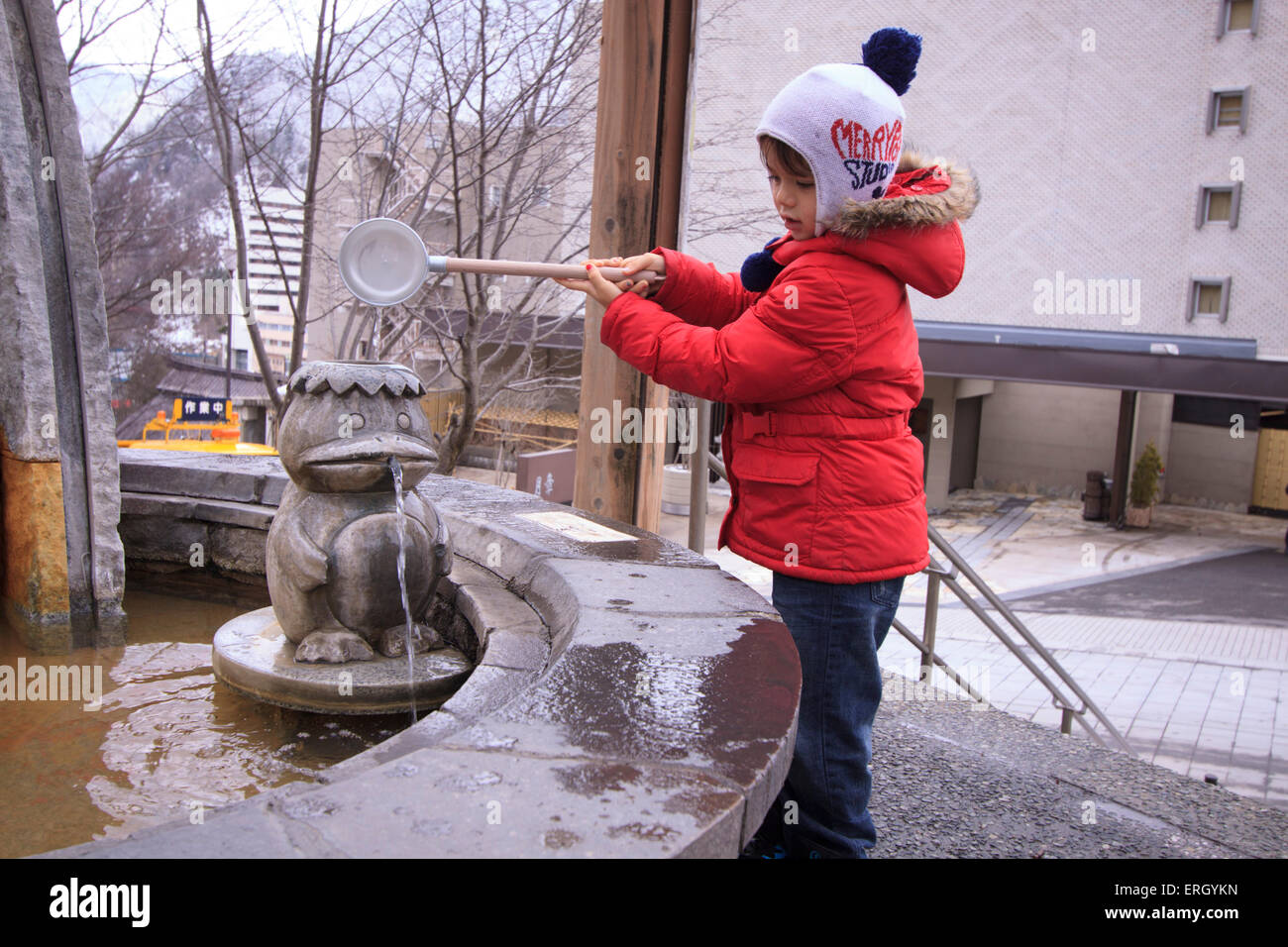 A young boy pours water to spill out of the mouth of a Kappa, water ...