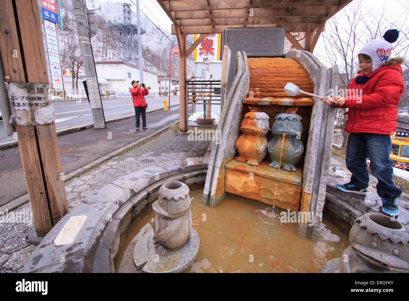 A young boy pours water to spill out of the mouth of a Kappa, water ...