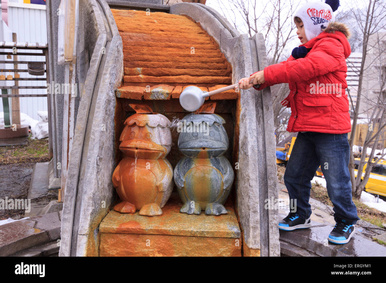 A young boy pours water to spill out of the mouth of a Kappa, water ...