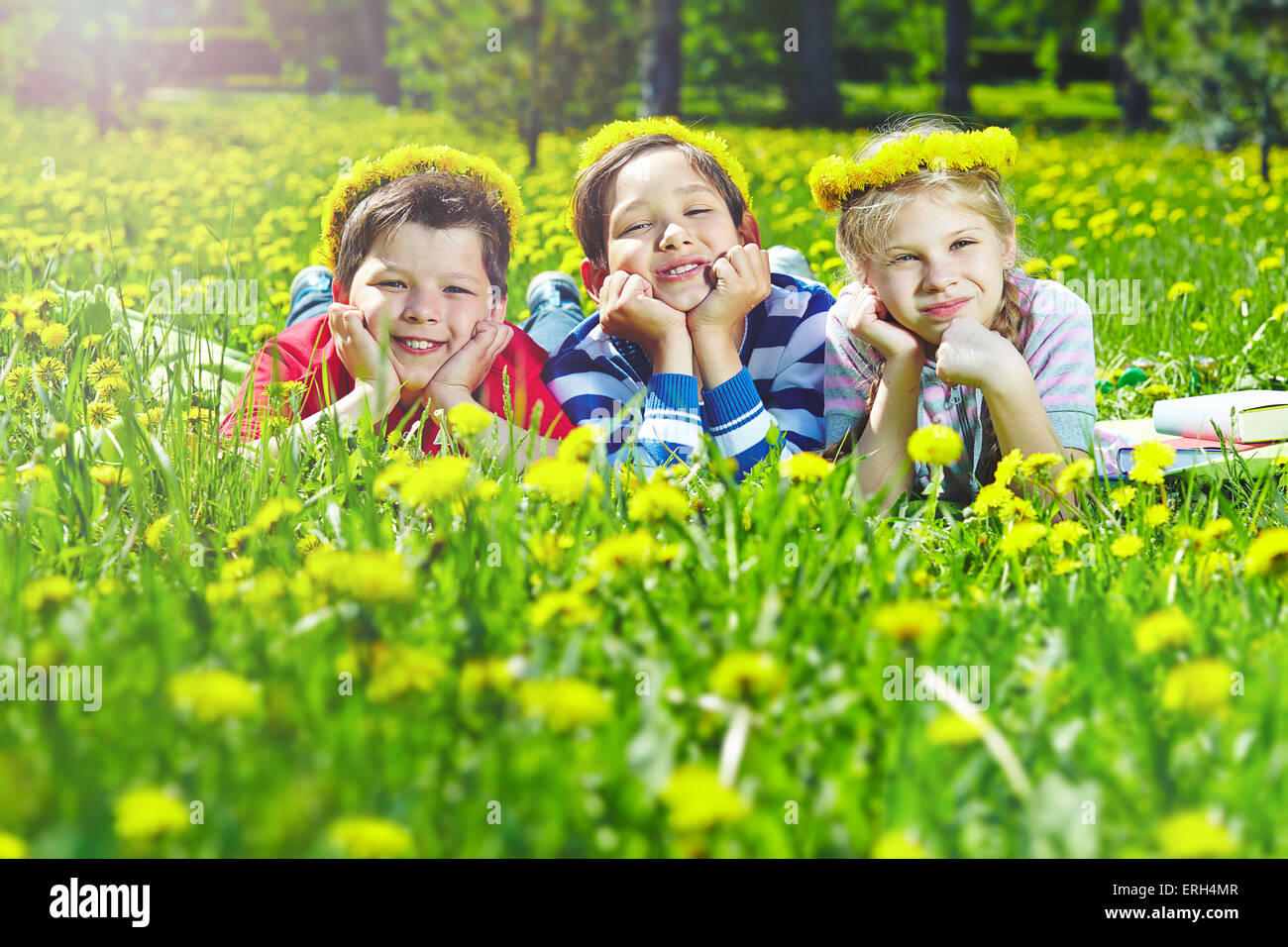 Happy children with dandelion wreaths having rest in natural ...