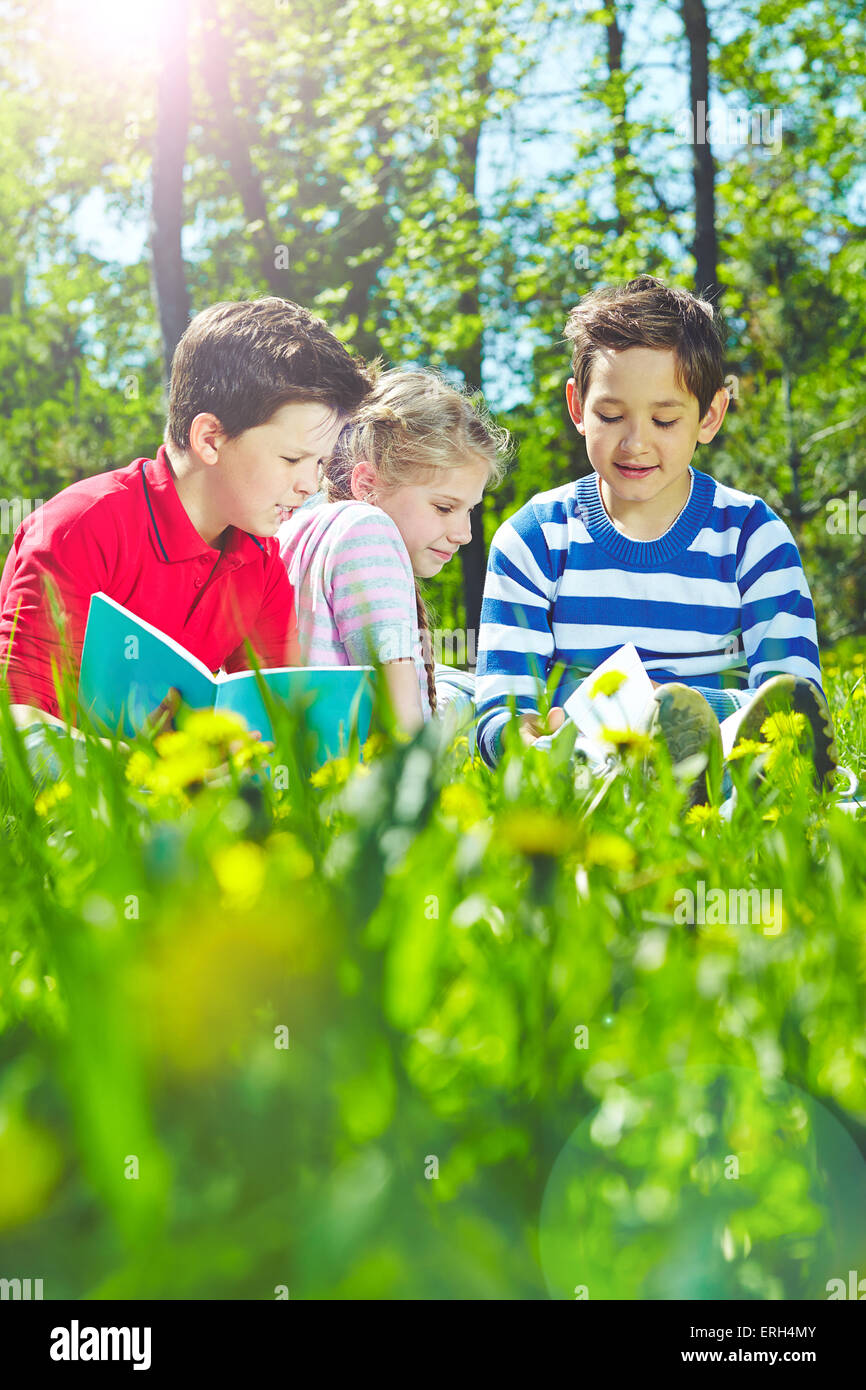 Adorable friends reading together in park Stock Photo - Alamy