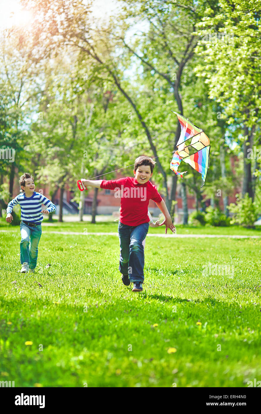 Cheerful boys playing with kite in park Stock Photo - Alamy