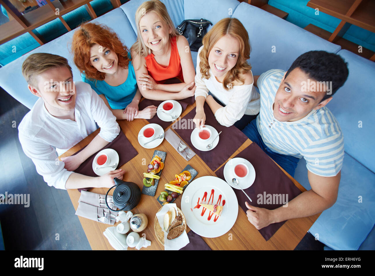 Joyful friends sitting by served table in cafe Stock Photo - Alamy