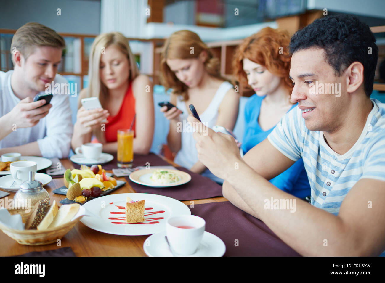 Modern teens with their cellphones sitting in cafe Stock Photo - Alamy