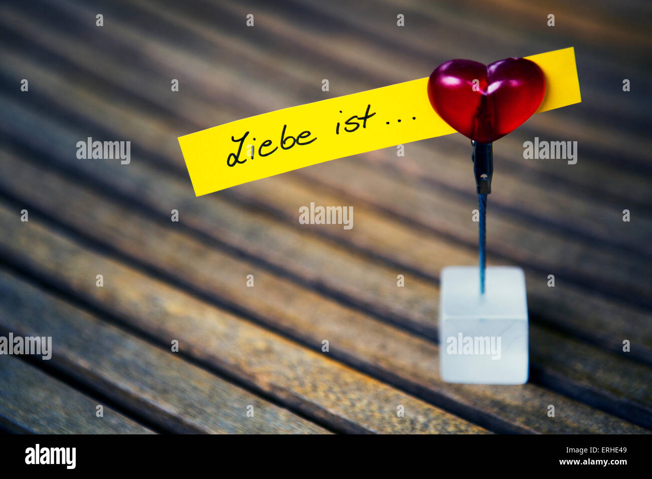 handwritten german quote "Liebe ist..." (love is...) clipped on a heart ...