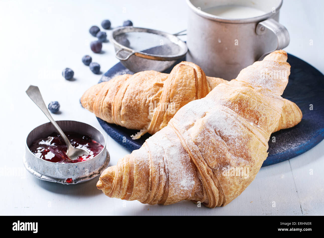 Two fresh baked croissants with sugar powder served with jam, aluminum ...
