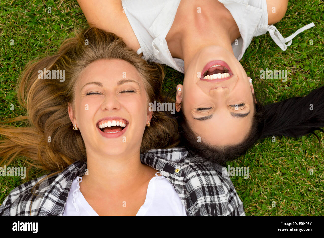Female best Friends lying on the grass and laughing Stock Photo - Alamy