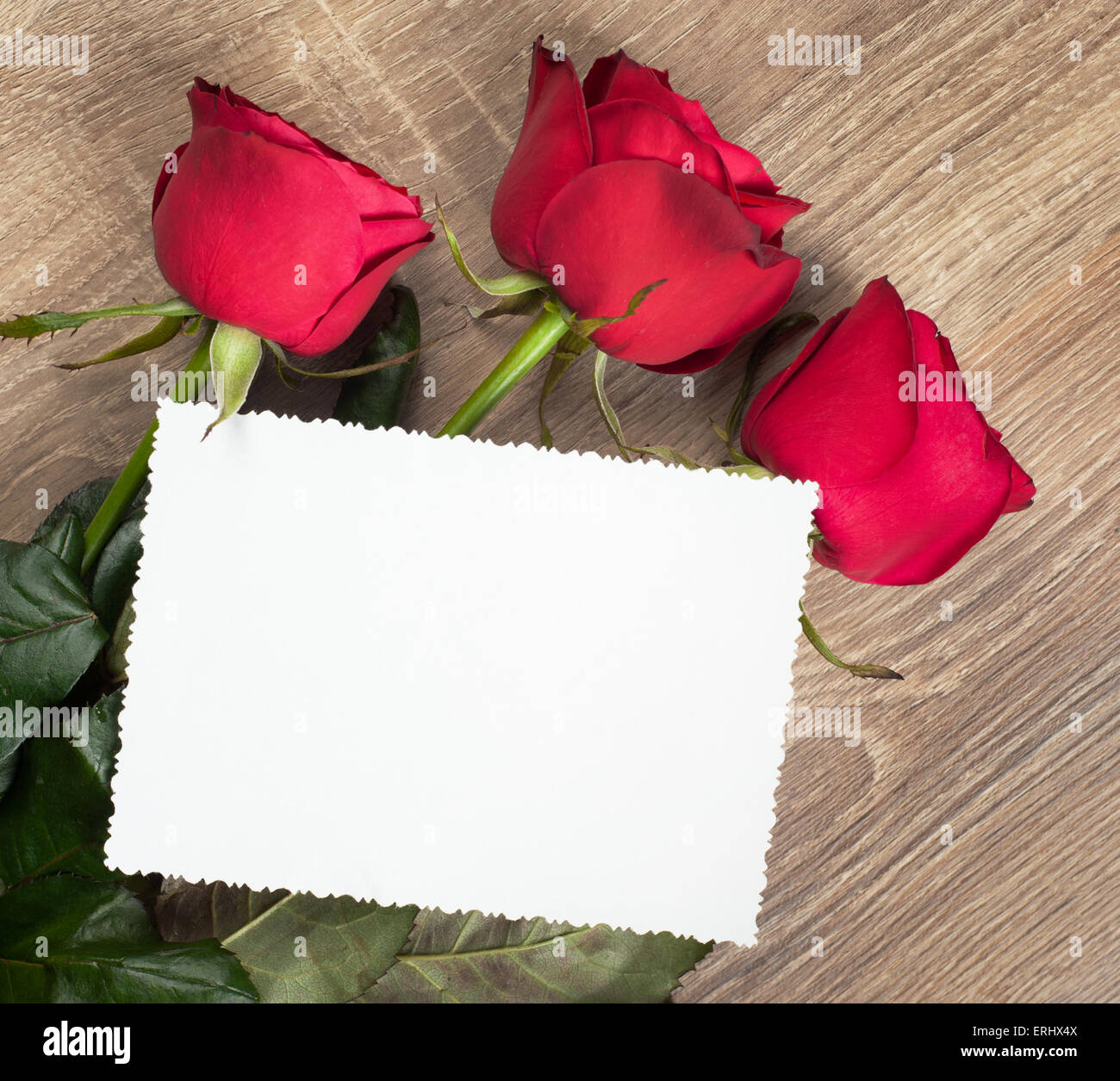 three red roses and blank sheet on wooden Stock Photo - Alamy