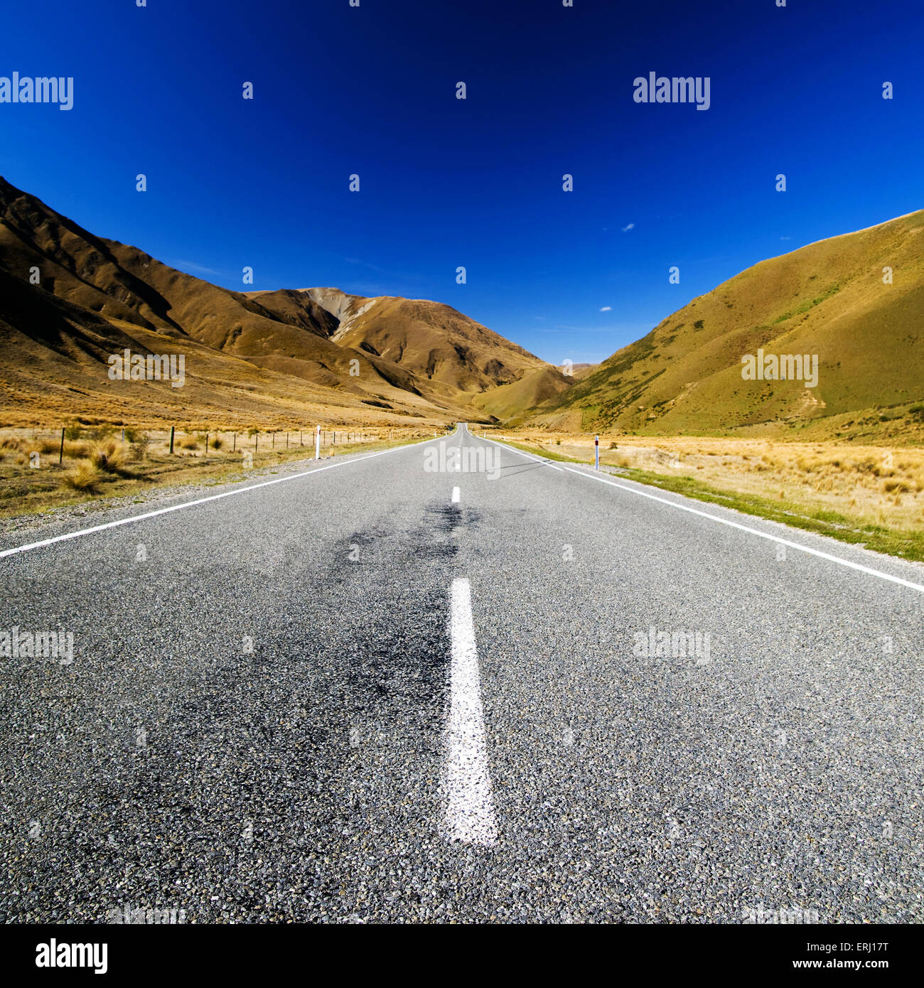 Continuous road in a scenic with mountain ranges afar Stock Photo - Alamy