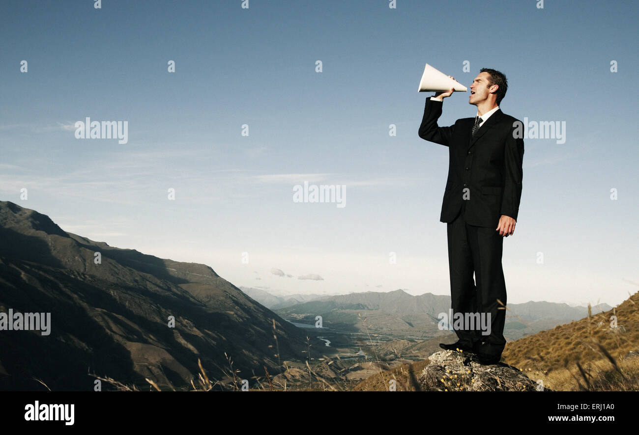 Businessman shouting on the top of the mountain Stock Photo - Alamy