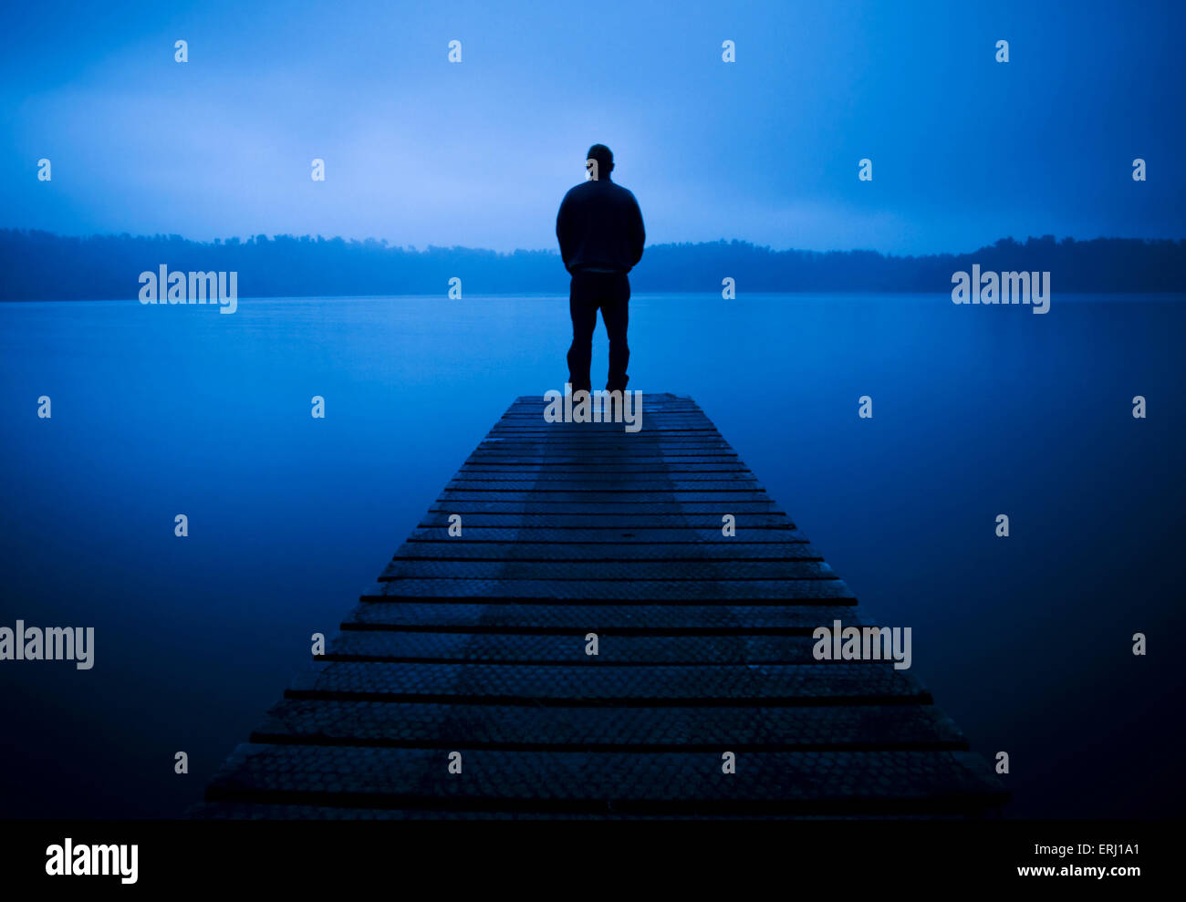 Man standing on a jetty by tranquil lake Stock Photo - Alamy