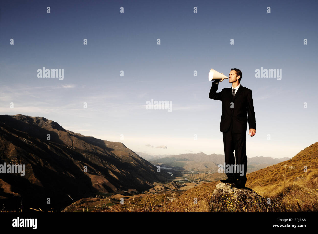 Businessman shouting on the top of the mountain Stock Photo - Alamy