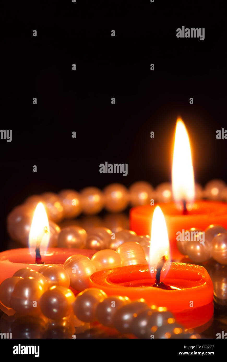 Burning candle and pearls on dark Stock Photo - Alamy