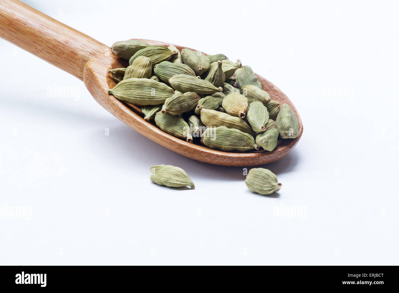 Cardamom pods in a wooden spoon on white background Stock Photo - Alamy