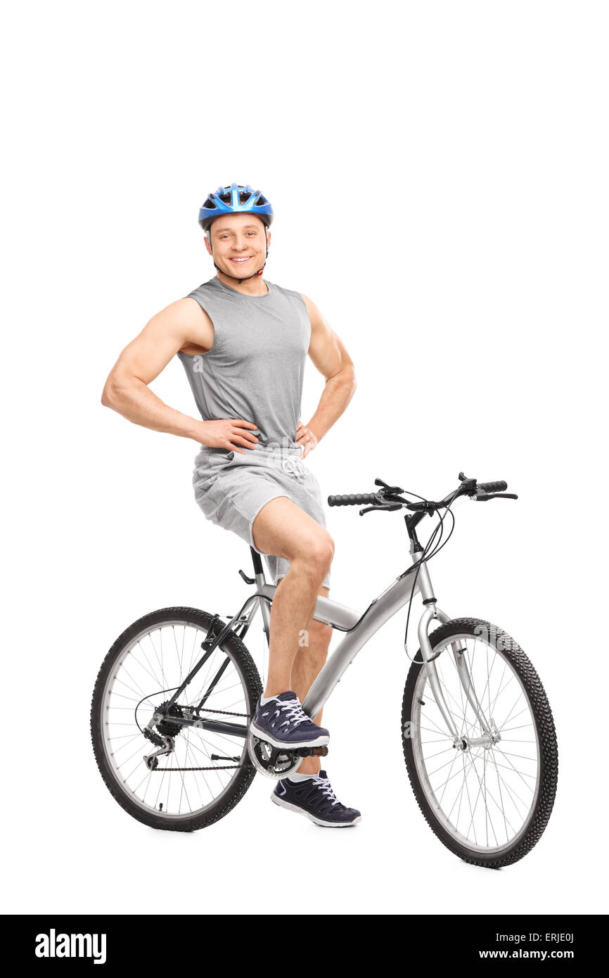 Full length portrait of a muscular young man posing seated on a bicycle ...
