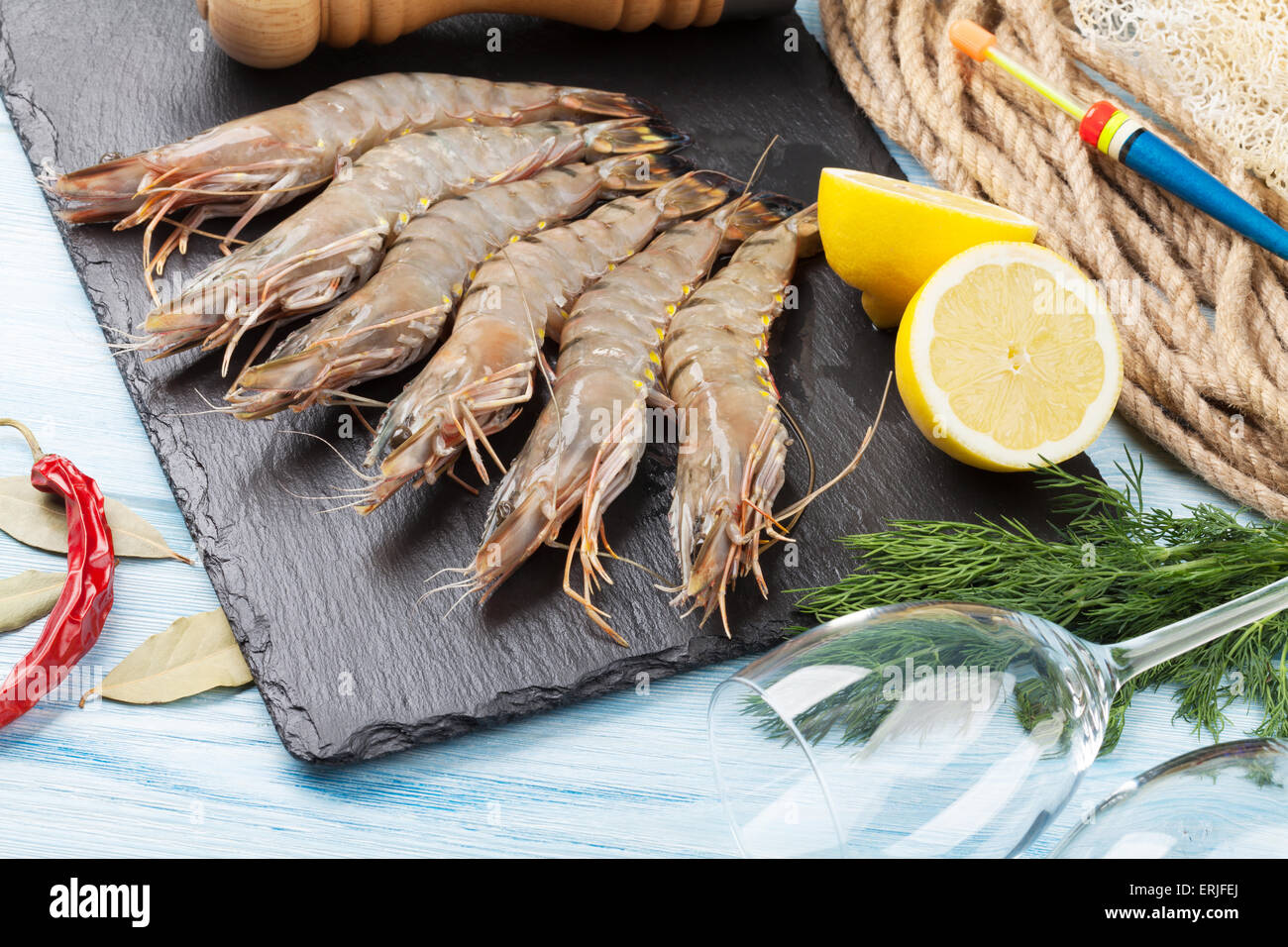 Fresh raw tiger prawns and fishing equipment on wooden table Stock ...