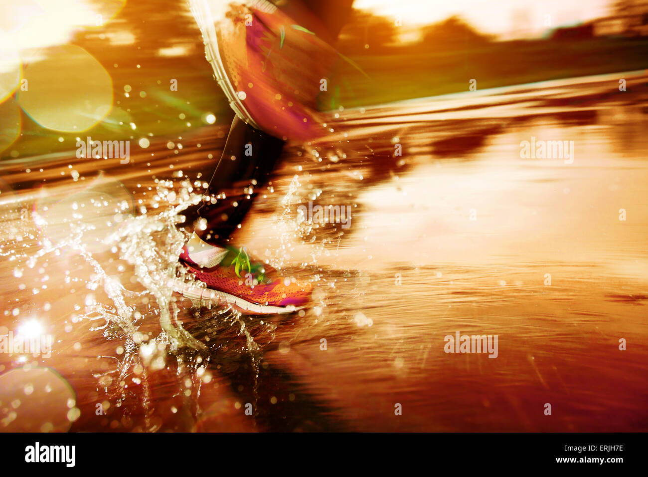 Single runner running in rain and making splash in puddle Stock Photo ...