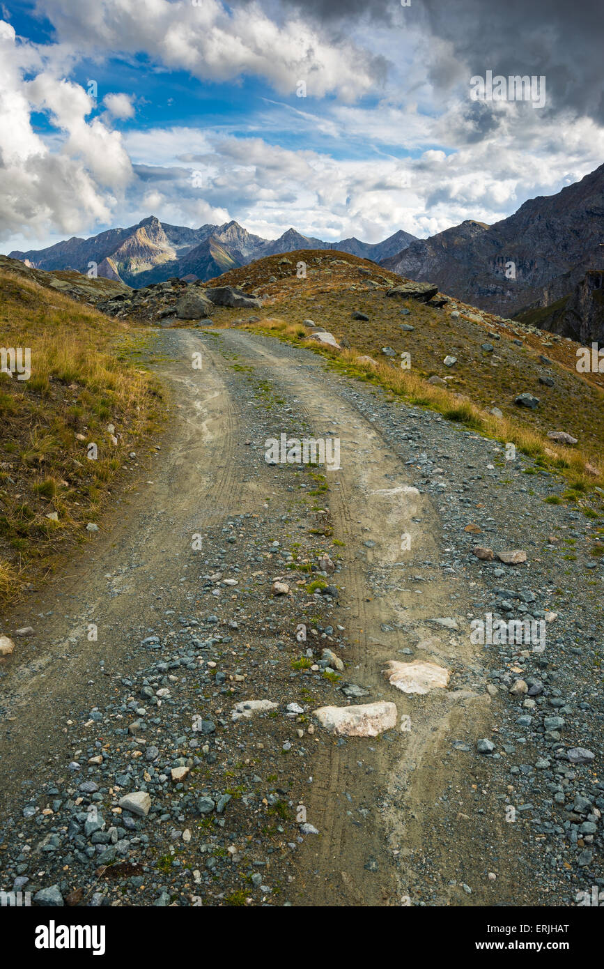Dirt mountain road crossing alpine slopes and meadows with dramatic ...