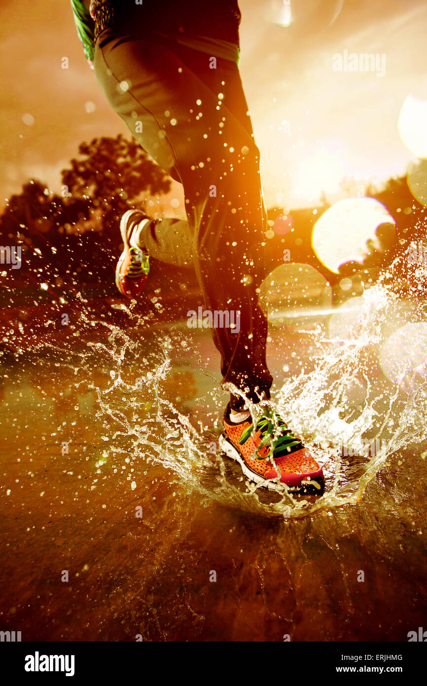 Single runner running in rain and making splash in puddle Stock Photo ...