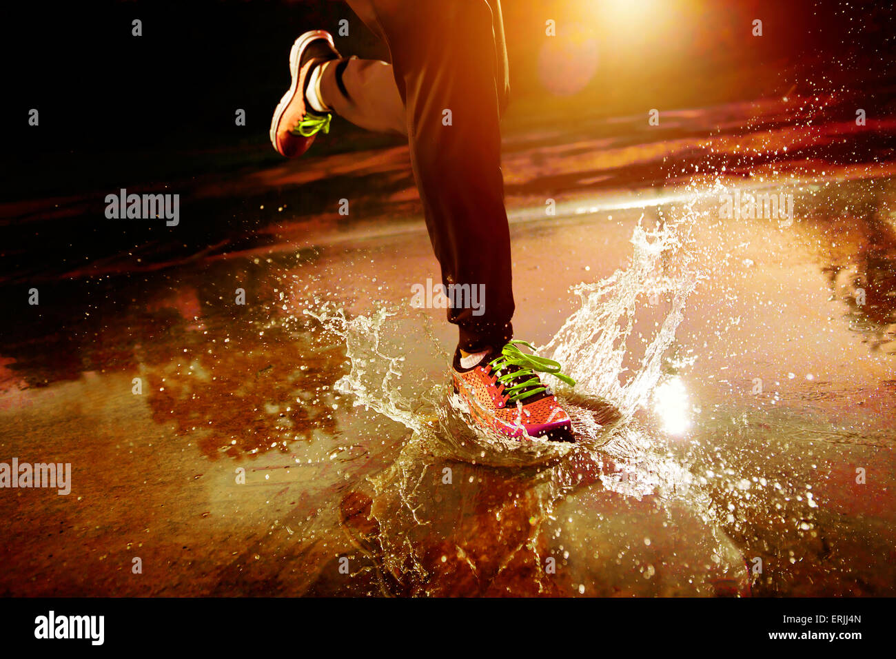 Single runner running in rain and making splash in puddle Stock Photo ...