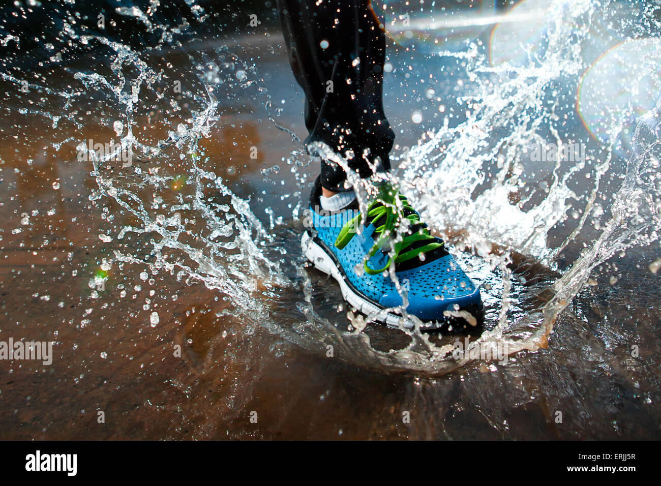 Single runner running in rain and making splash in puddle Stock Photo ...