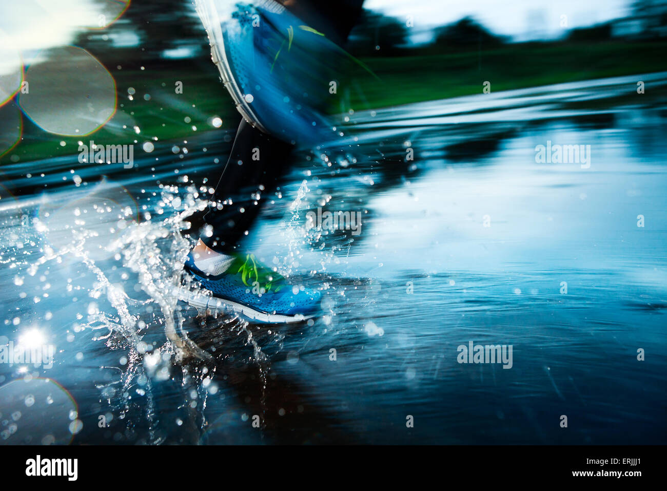 Single runner running in rain and making splash in puddle Stock Photo ...