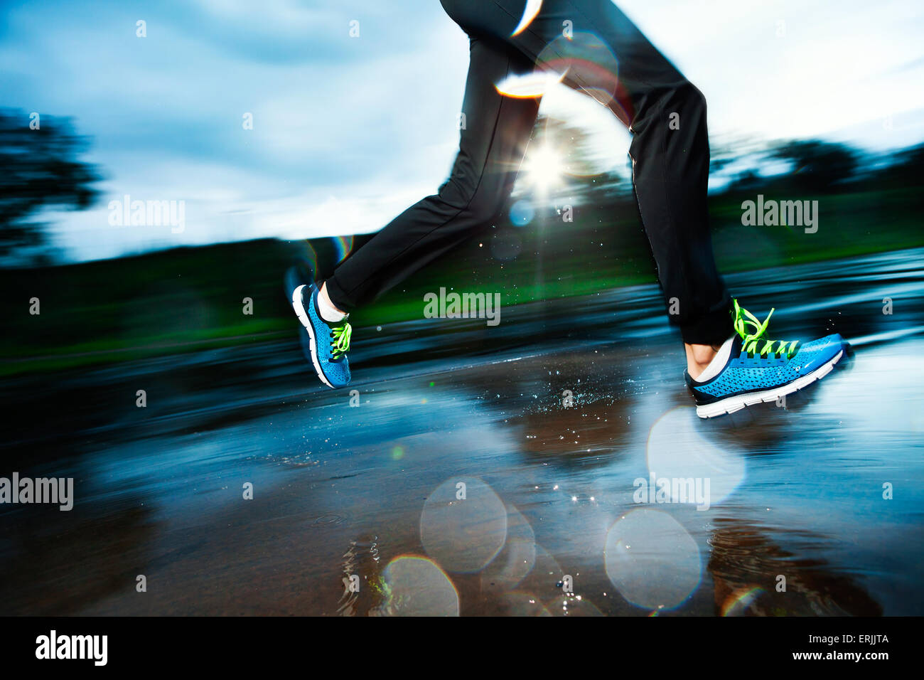 Single runner running in rain and making splash in puddle Stock Photo ...