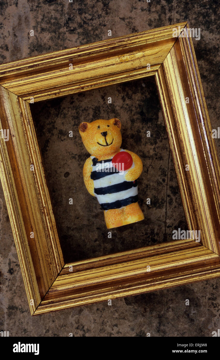 Golden frame lying on rough card and containing model of teddy bear in ...