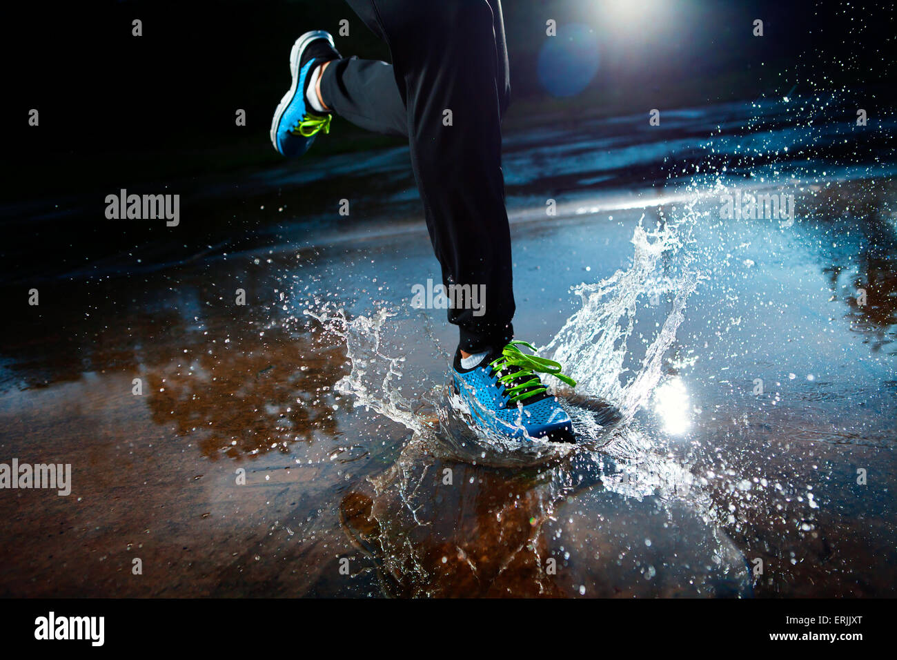 Single runner running in rain and making splash in puddle Stock Photo ...